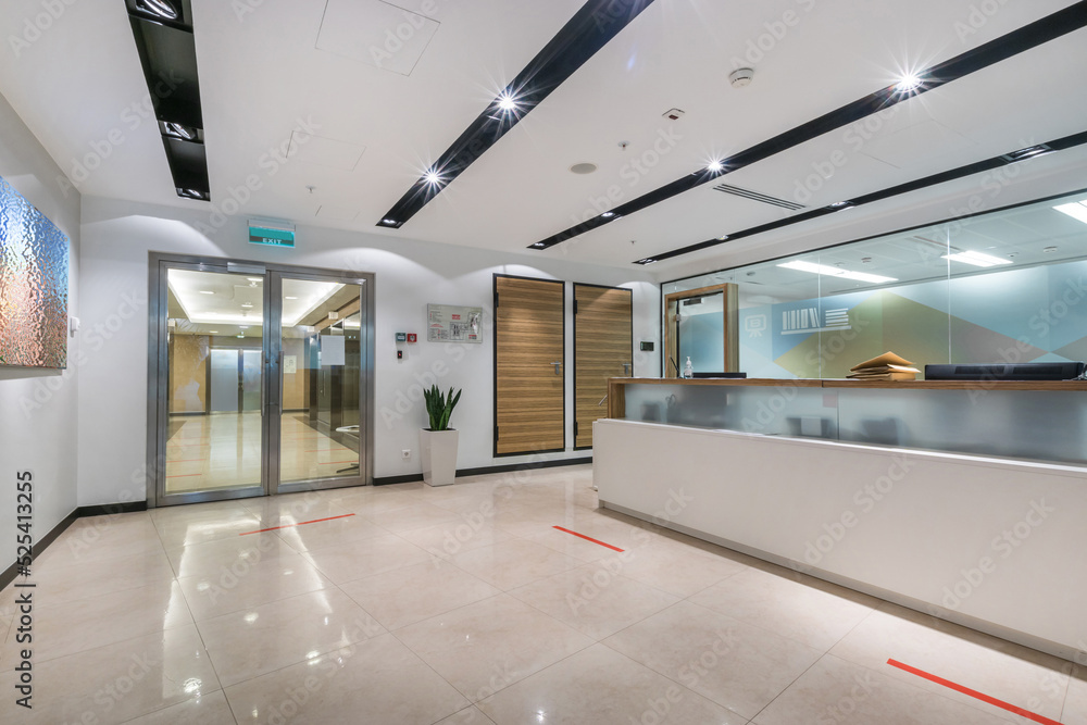 A spacious, bright office hall with a reception desk, glass doors and a ...