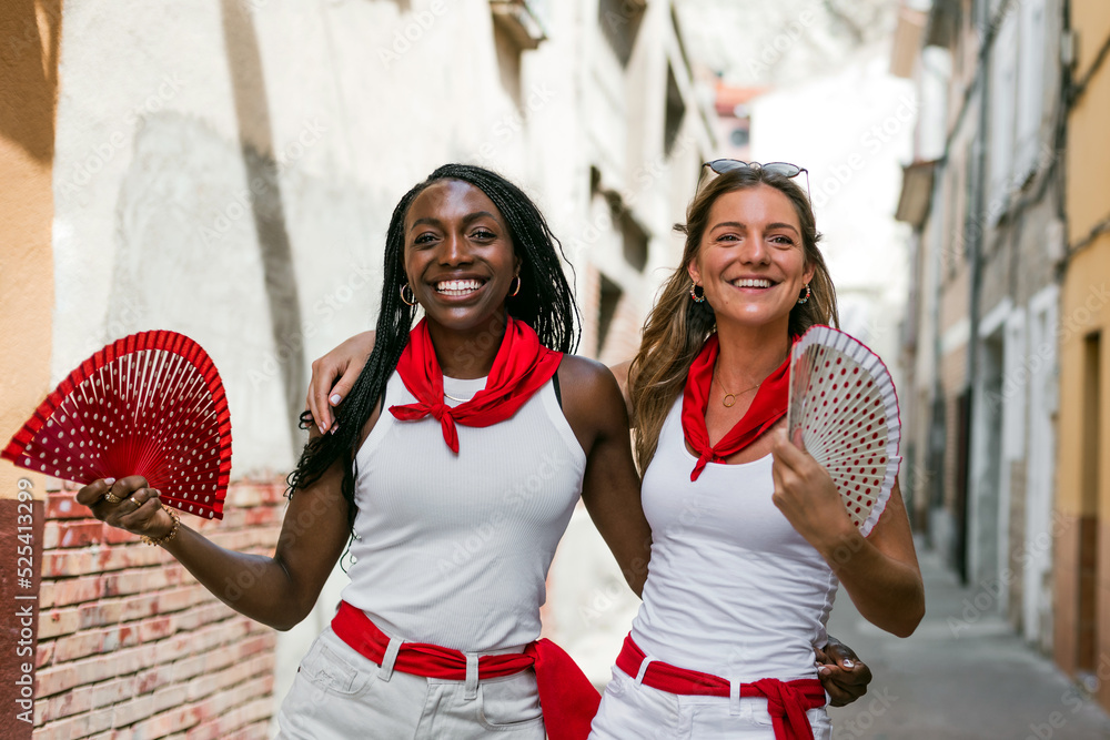 two young caucasian and afro-american girls with their hand fans enjoy ...