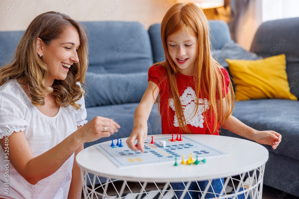 Mother and daughter having fun playing ludo board game at home Stock ...