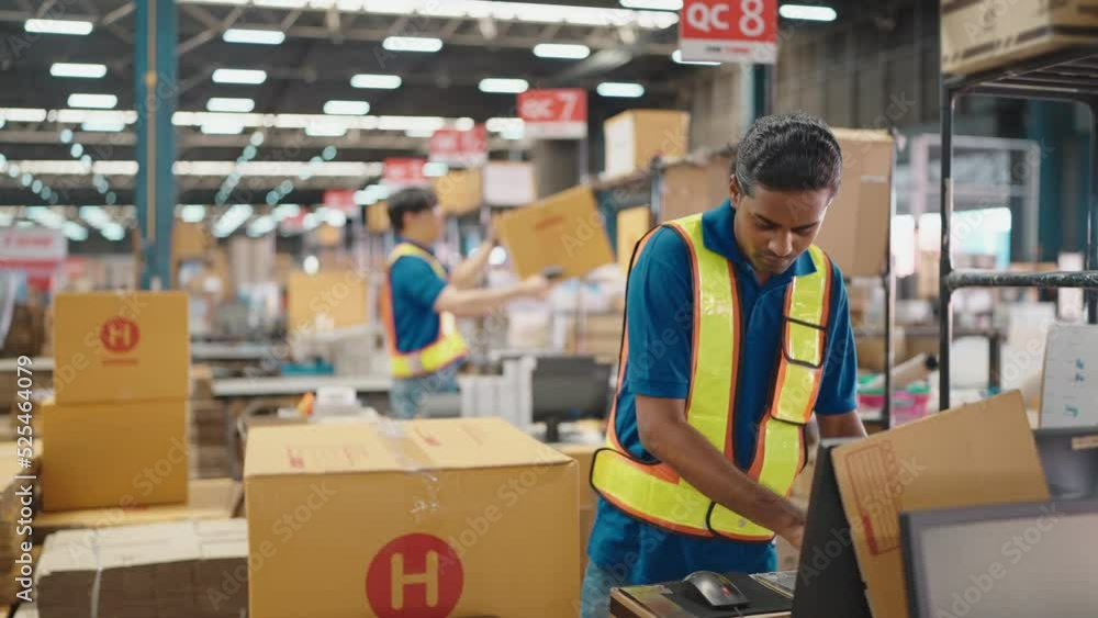 Warehouse worker using a QR code reader, scanning parcels into the ...