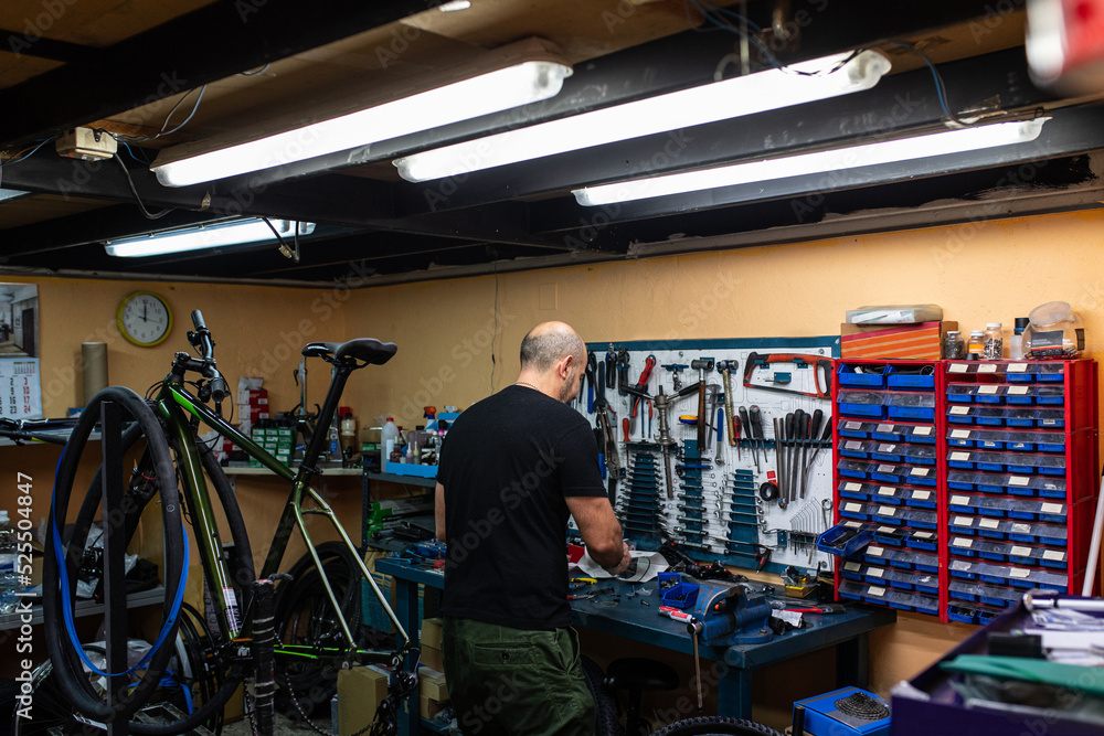 Bald mechanic working in bike workshop Stock Photo | Adobe Stock