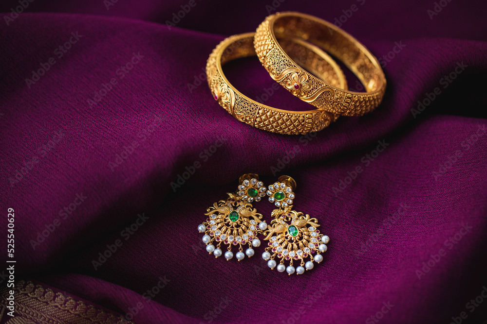 Golden bangles with Gold earrings on a purple saree background Stock ...