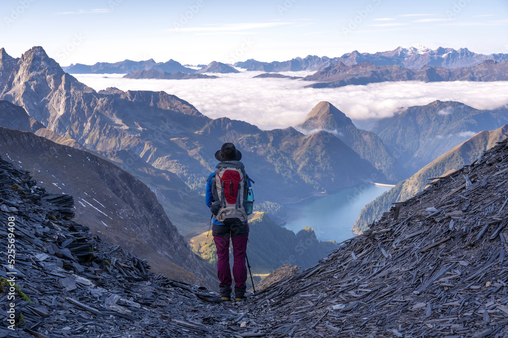 Woman looking into valley of mountains, lakes and clouds, Greina ...