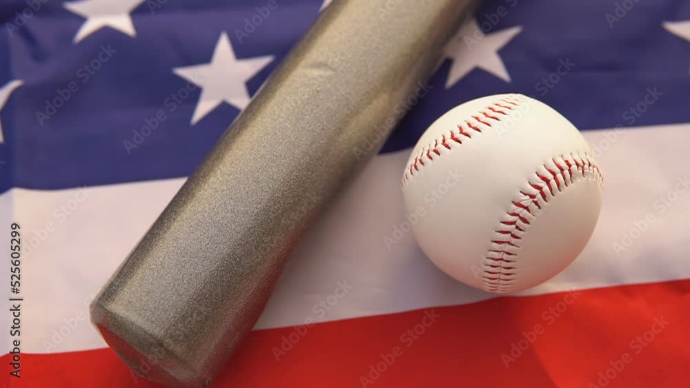 White leather ball and baseball bat laying on flag of the United States ...