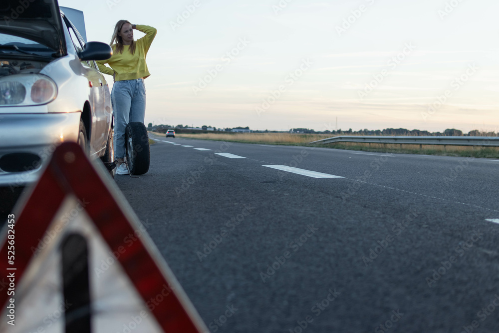 girl in stands near the rear wheel of the car and rolls a spare wheel ...
