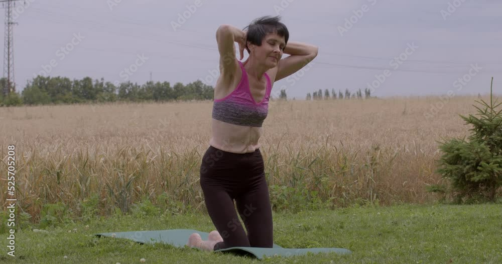 Woman age makes body movement in training. She twists her spine, hands ...