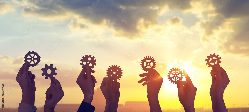 Hands holding of gear from at sunset sky background. teamwork industry ...