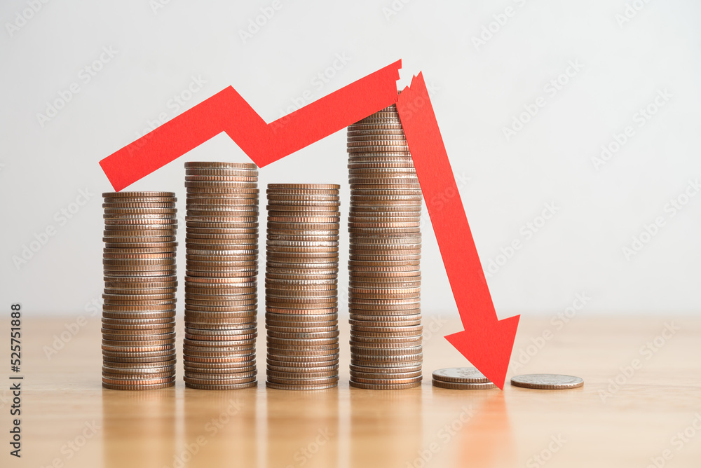 Stack coins and red arrow graph chart falling down on wooden table ...
