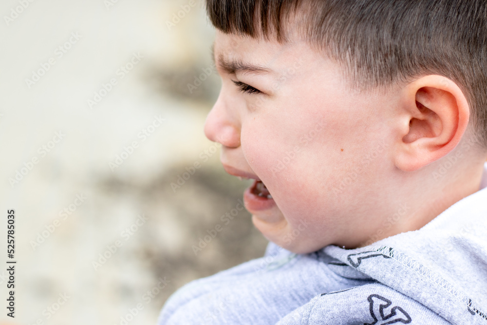 upset unhappy kid is crying out sitting outside on park bench ...