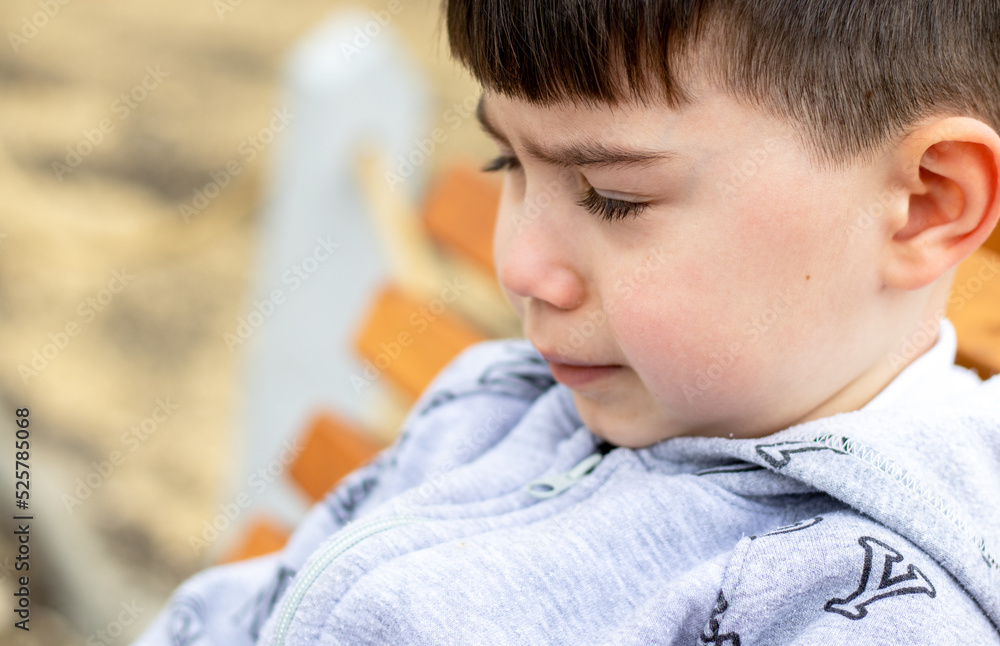 upset unhappy kid is crying out sitting outside on park bench ...