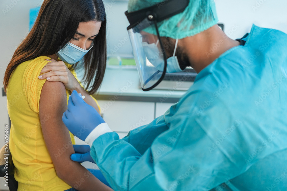 Doctor with hazmat suit and protective gloves giving patient a vaccine ...