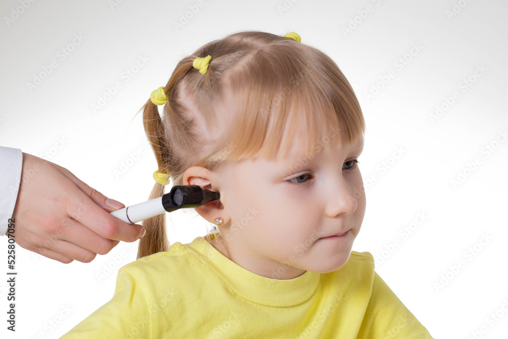 The doctor examines the ear canal of a little caucasian girl 5 years ...