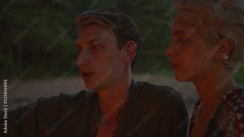 Close up view of millennial happy couple sit next to campfire in ...