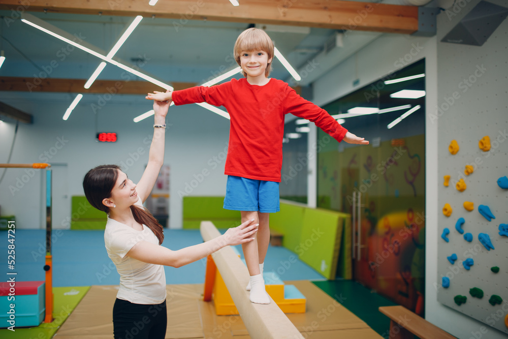 Kids doing balance beam gymnastics exercises in gym at kindergarten or ...