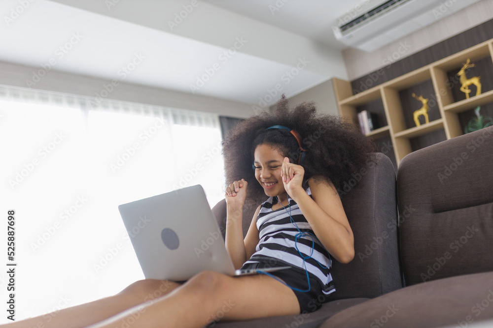 Excited cheerful young Black woman using laptop computer on sofa at ...