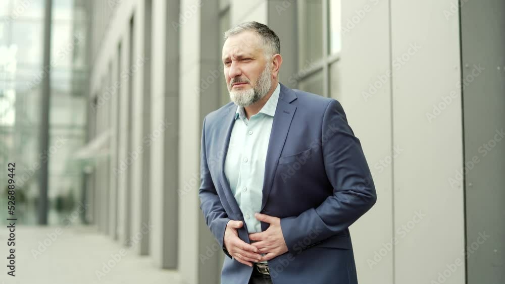 Mature man abdominal pain standing on city street near office building ...