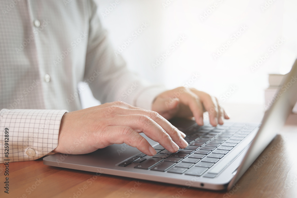 businessman using laptop and his hand is typing on keyboard while ...