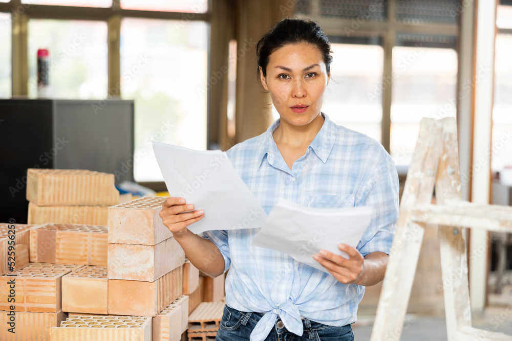 Asian female architect controling works on a construction site indoors ...