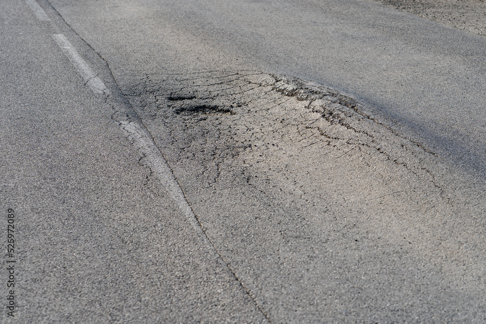 Broken road with holes and cracks built in countryside on hot sunny day ...