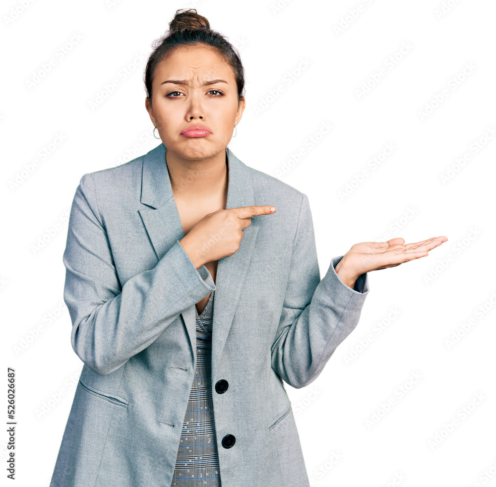 Young hispanic girl pointing open palm with finger depressed and worry ...