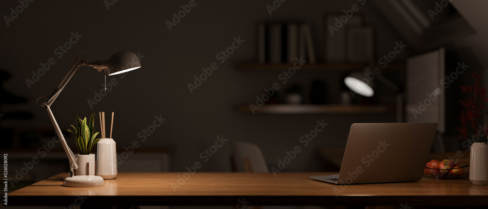 Modern dark wooden office desk at night under the warm light from table ...