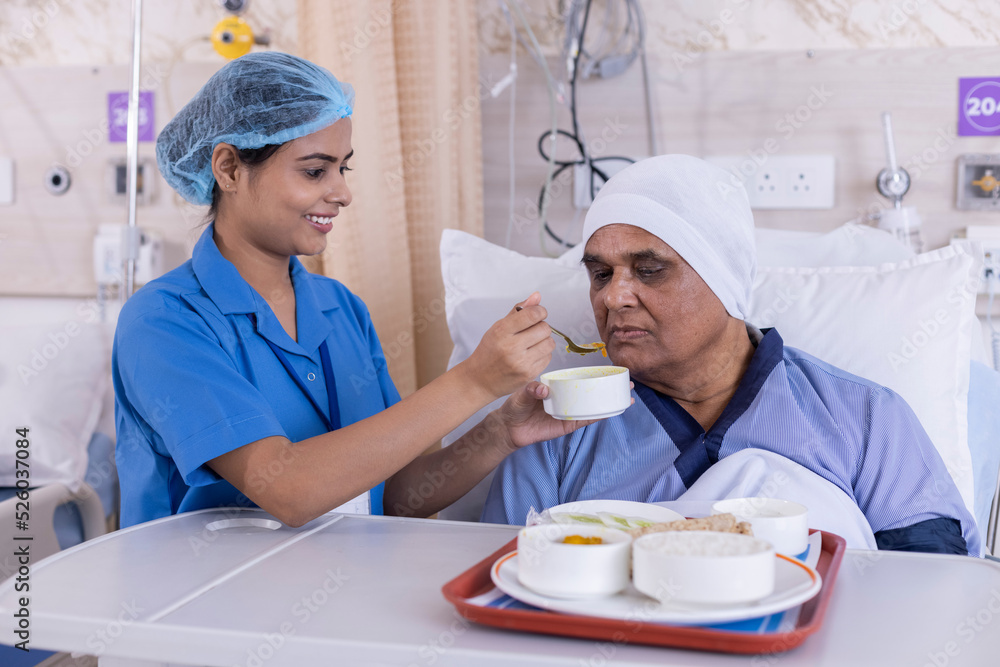 Young nurse feeding the senior patient at hospital Stock Photo | Adobe ...