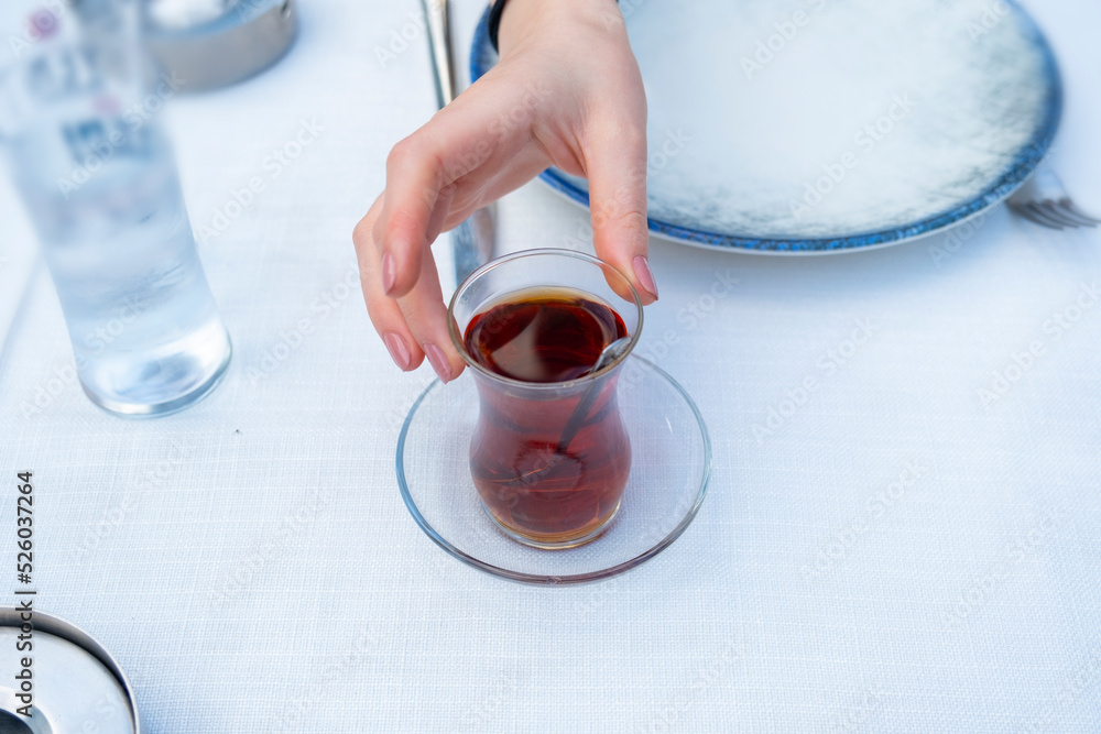 Woman hand holding Turkish tea, Turkish raki on the background, Turkey ...