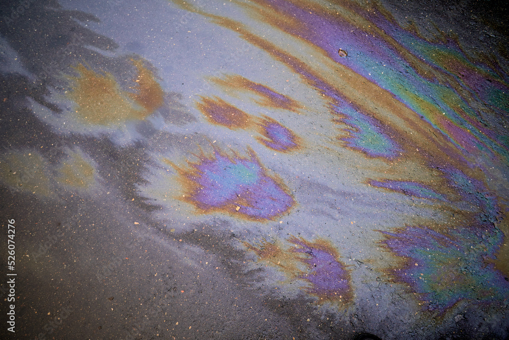 Oil stain on the asphalt, rainbow-shaped colored gasoline stains on an ...