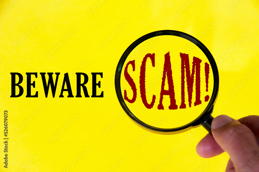 Beware scam text on yellow cover with hand holding magnifying glass ...