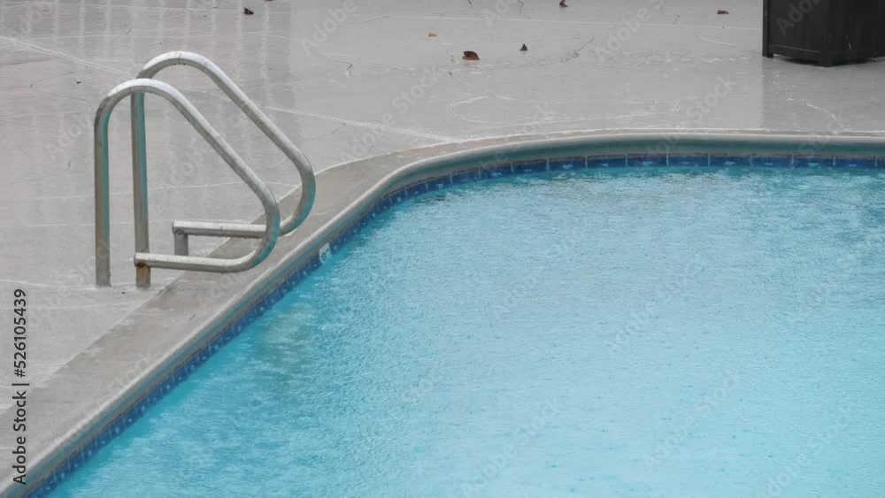 Rain drops falling on water surface of blue swimming pool, rainy day in ...