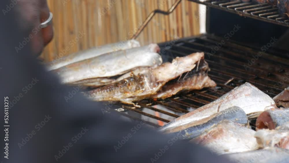 Vidéo Stock An African American cooks raw fish on the grill. African ...