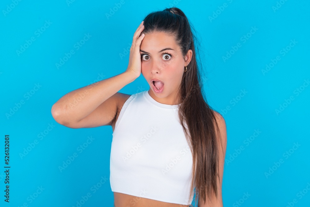 Embarrassed Beautiful Brunette Woman Wearing White Tank Top Over Blue