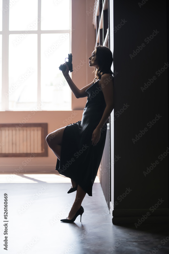 Side view of sensual woman in dress holding handgun at home Stock Photo ...