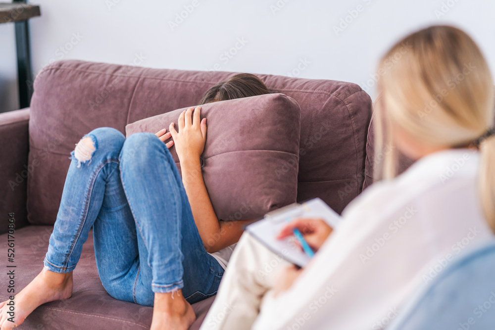 unhappy crying teenage girl talks to psychologist, hugging pillow, at ...