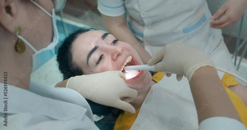 Woman dentist works with a microscope in mouth of patient's cavity in ...