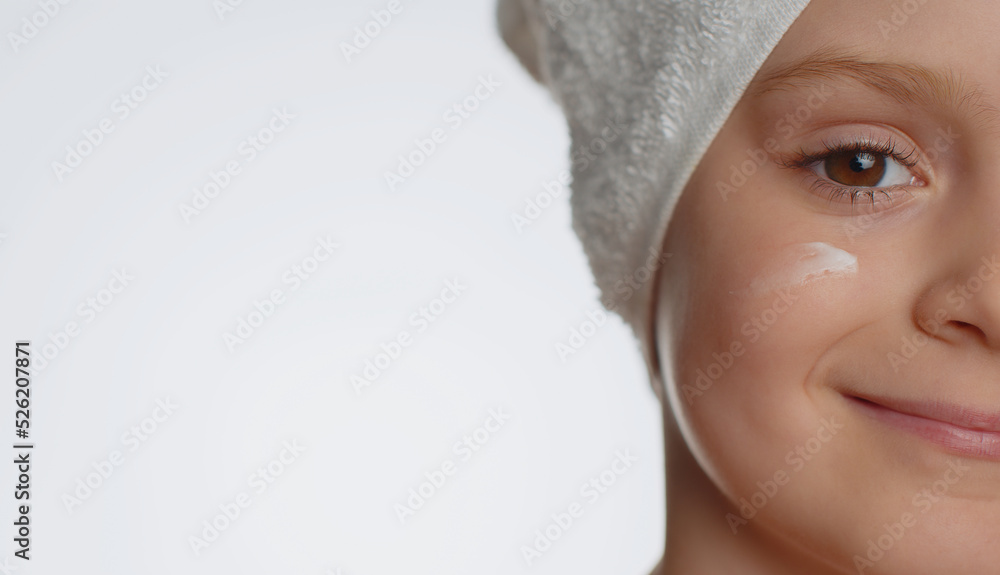 Young child girl applying cleansing moisturizing cream on cheekbones ...