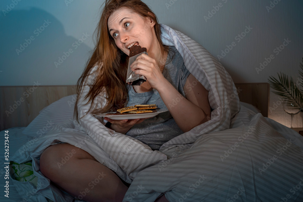 Woman late-night snacking in bed at home waking up hungry at night ...