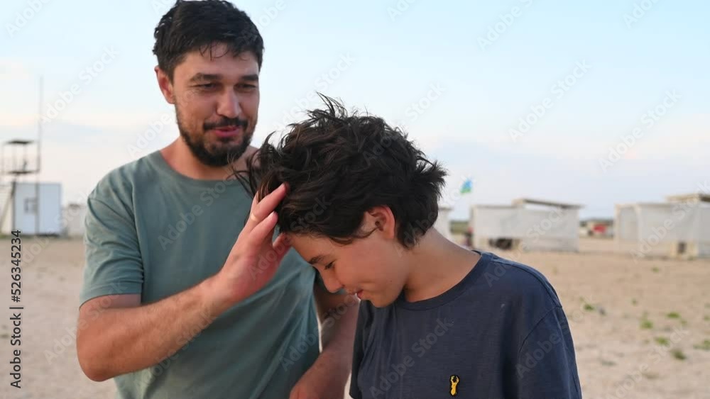 A dad on a walk with his teenage son. A father lovingly pats his adult ...