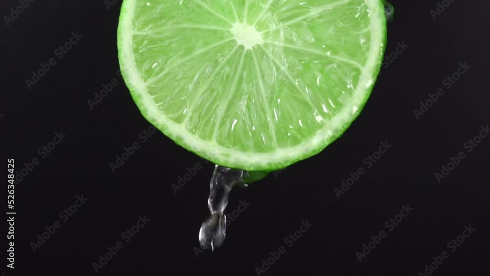 Water drops falling from juicy lime on black background. Lime slice and ...