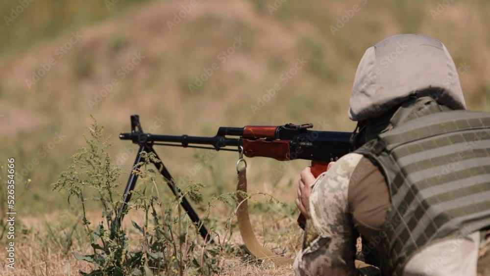 Military man in green uniform vest unloading gun with machine gun in ...