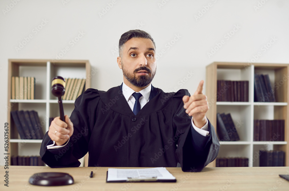 Portrait of stern judge knocking on judge's gavel passes sentence and ...