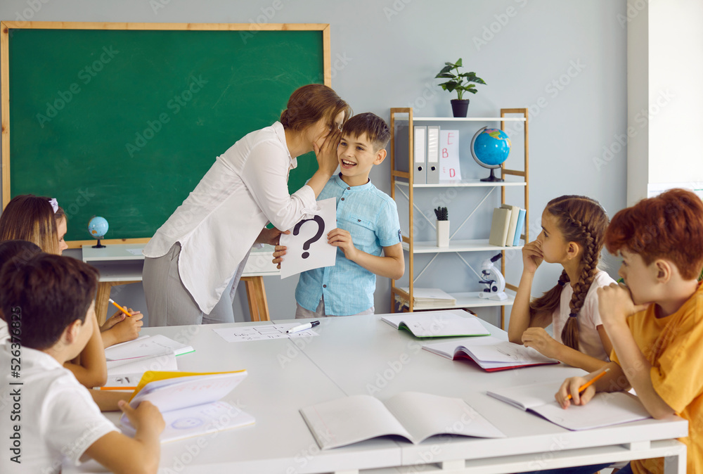 Creative lesson. Friendly female teacher whispers in ear of little ...