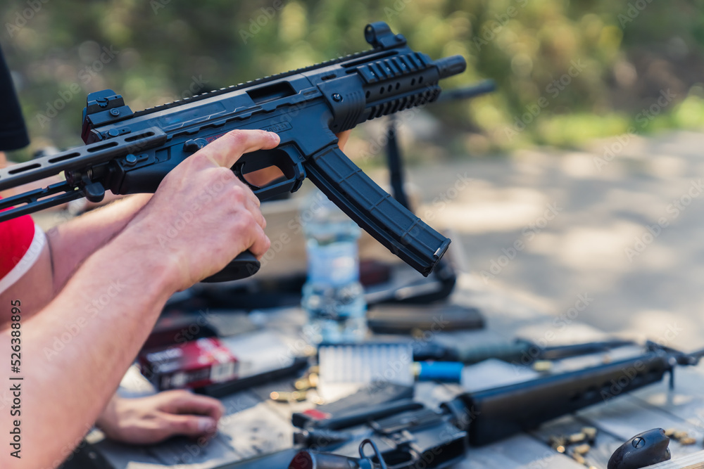 Hands of an unrecognizable caucasian person holding a black rifle and ...