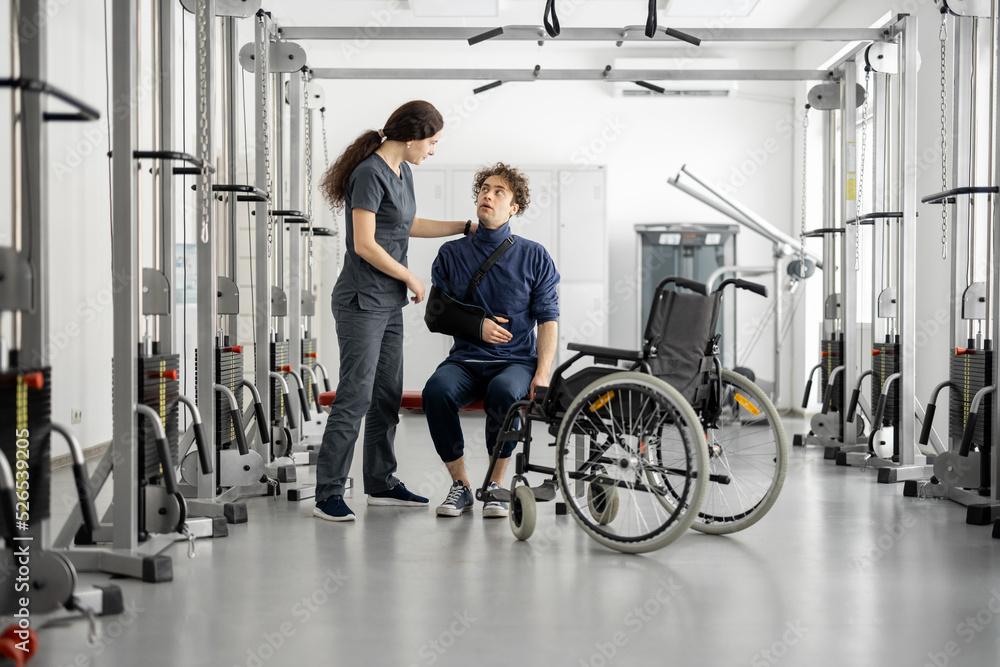 Rehabilitation specialist talking with a guy on wheelchair at ...