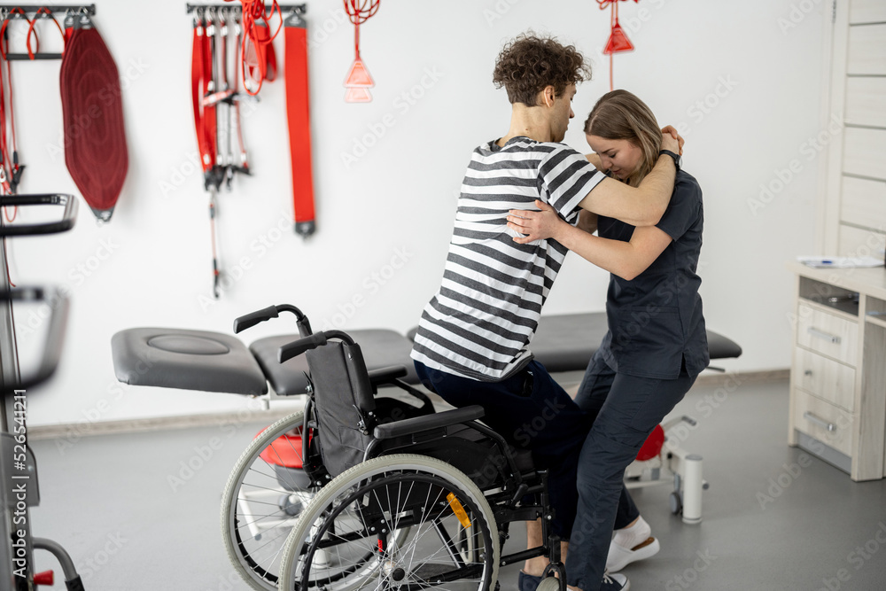Nurse of the rehabilitation center helps man to get up from a ...