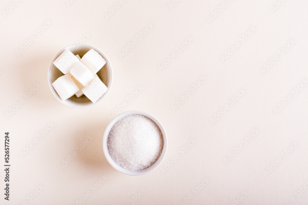Sugar cubes and granulated sugar in bowls. Choosing between types of ...