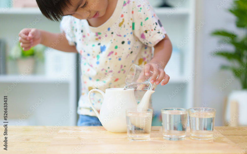 Hands of blurred asian little boy pouring the water to the cup in ...