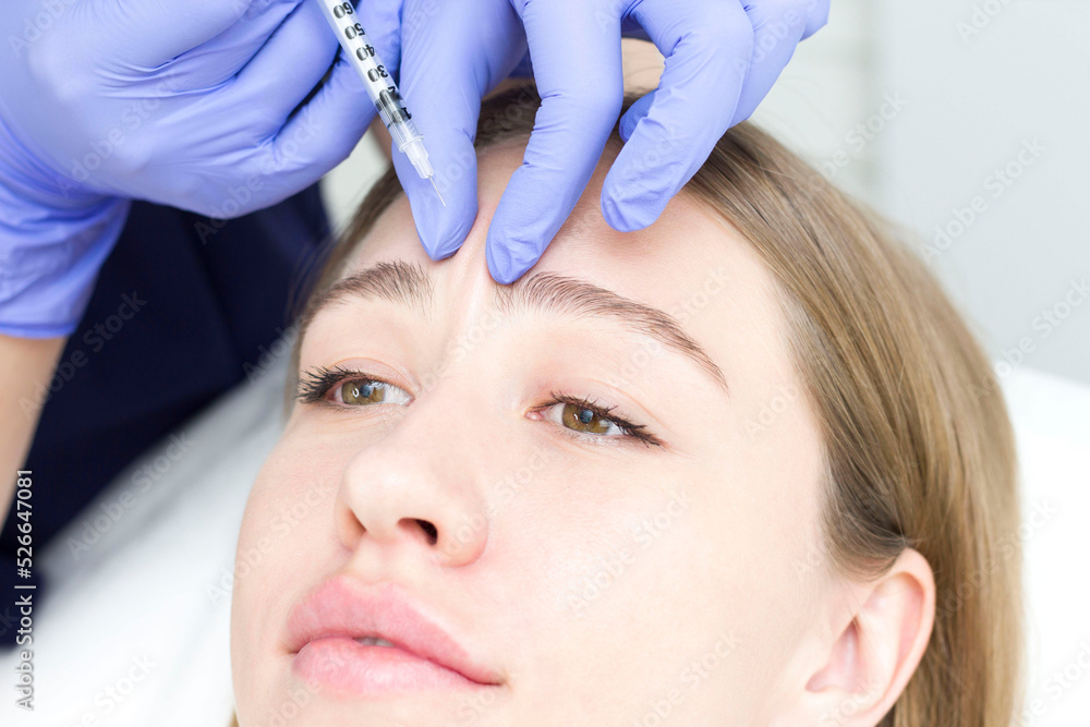 Close-up of the hands of an expert cosmetologist injecting botox into a ...