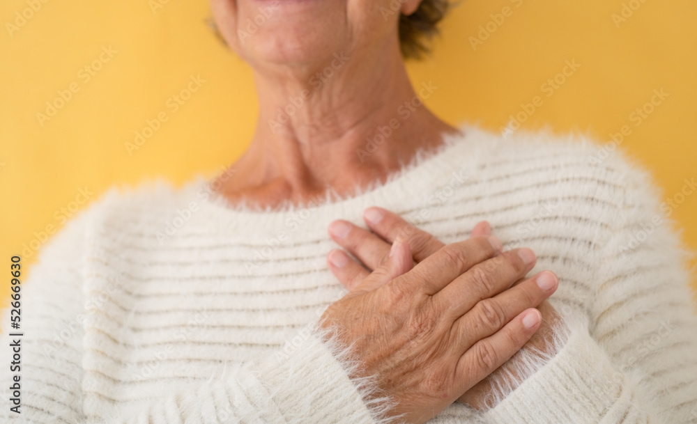 Closeup on senior woman white dressed with hands over her heart ...