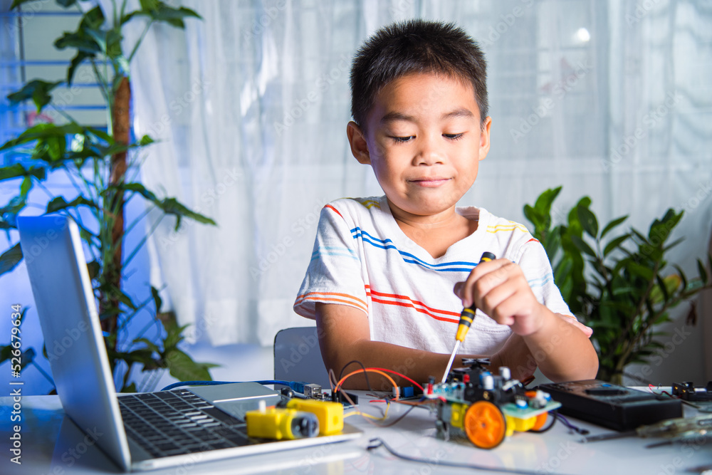 Asian kid boy assembling the Arduino robot car homework project at home ...
